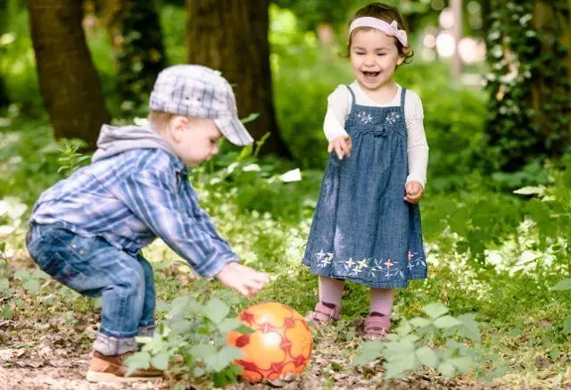 Малко момиченце и момче играят топка в гората на почивка външно меню и развлечения