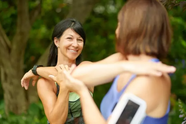 Casal de mulheres savy mulheres em seus quarenta se preparando para uma corrida por streching seus músculos