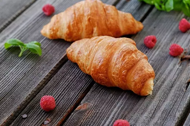 Dve čerstvé croissanty na drevenom stole.